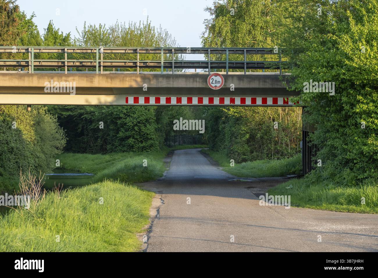 Low concrete bridge crossing a country road with a height limit and ...