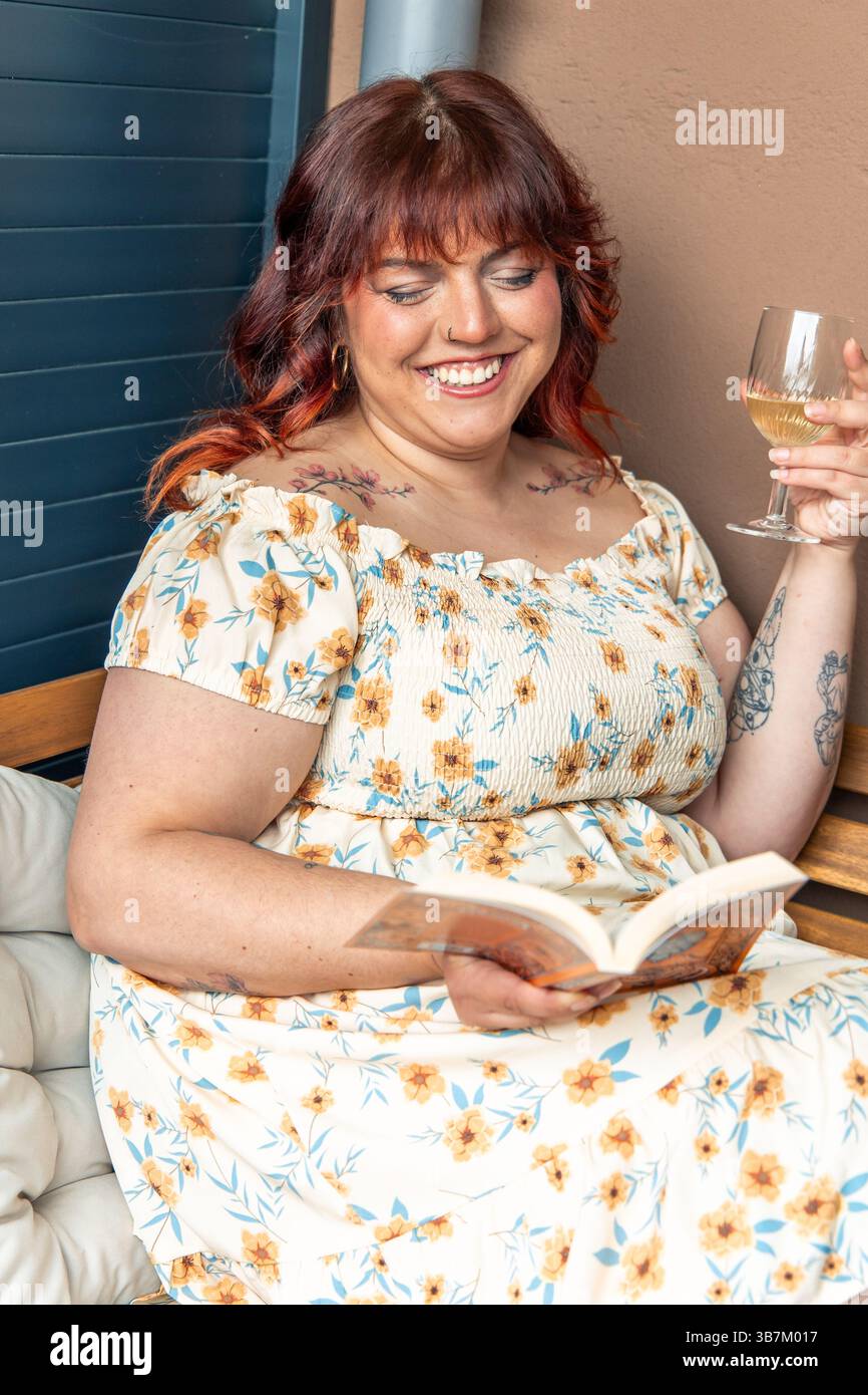 Smiling curvy woman with vibrant red hair, wearing a floral dress ...