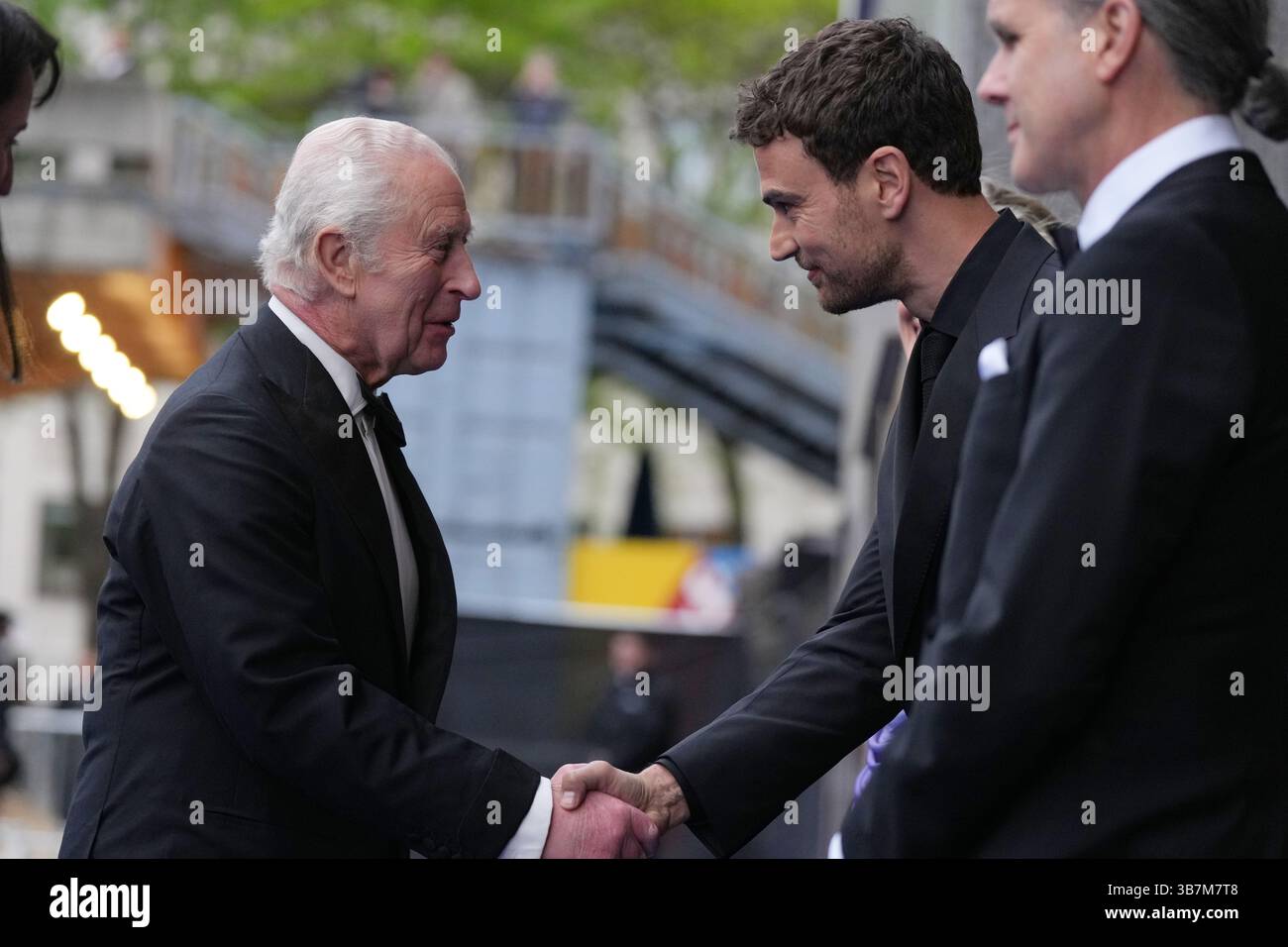 King Charles III (left) shakes hands with actor Theo James as he ...