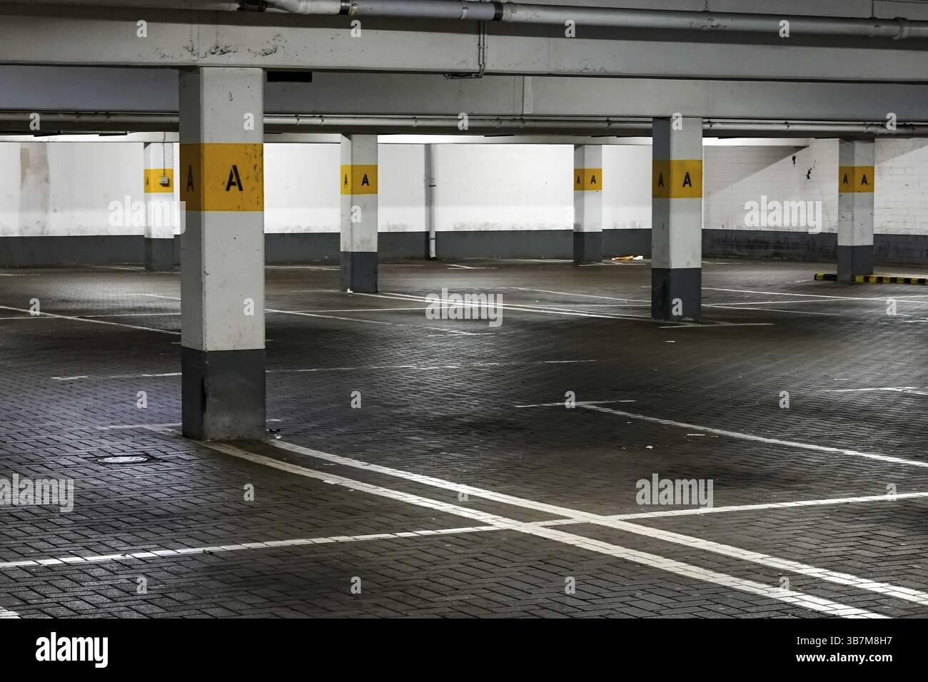 Large empty parking garage showing concrete pillars and white lines ...