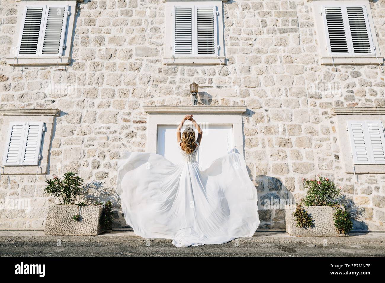 A bride in a wedding dress is spinning on the old street of Perast, her ...