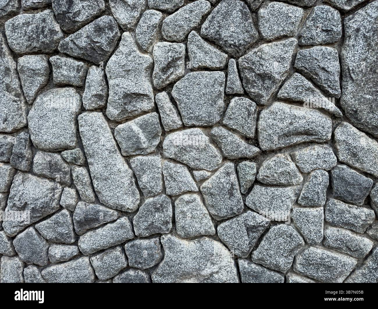 Close-up of irregular grey stone wall with visible texture and natural ...