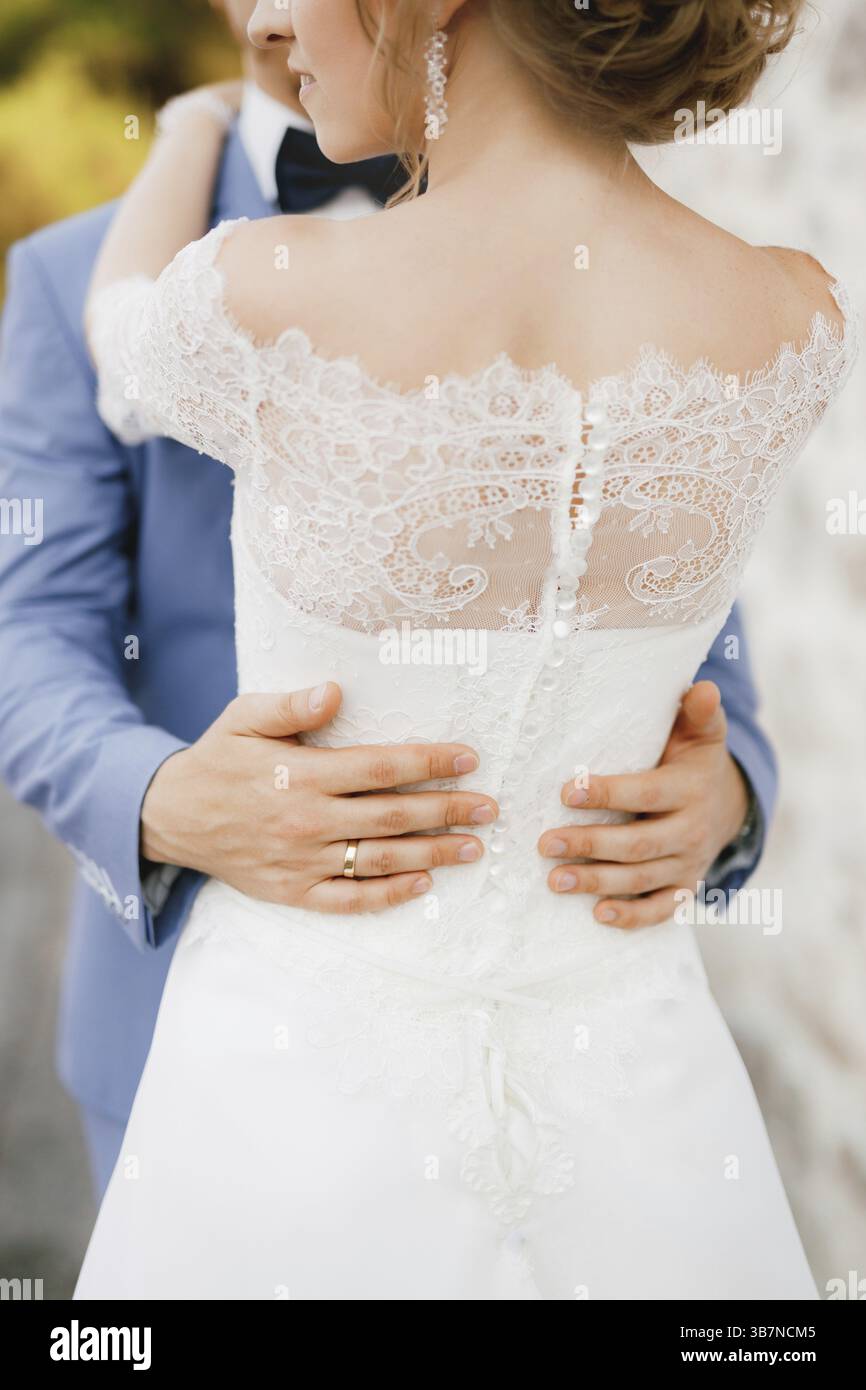 The bride and groom hug, the groom's hands on the waist of the bride in ...