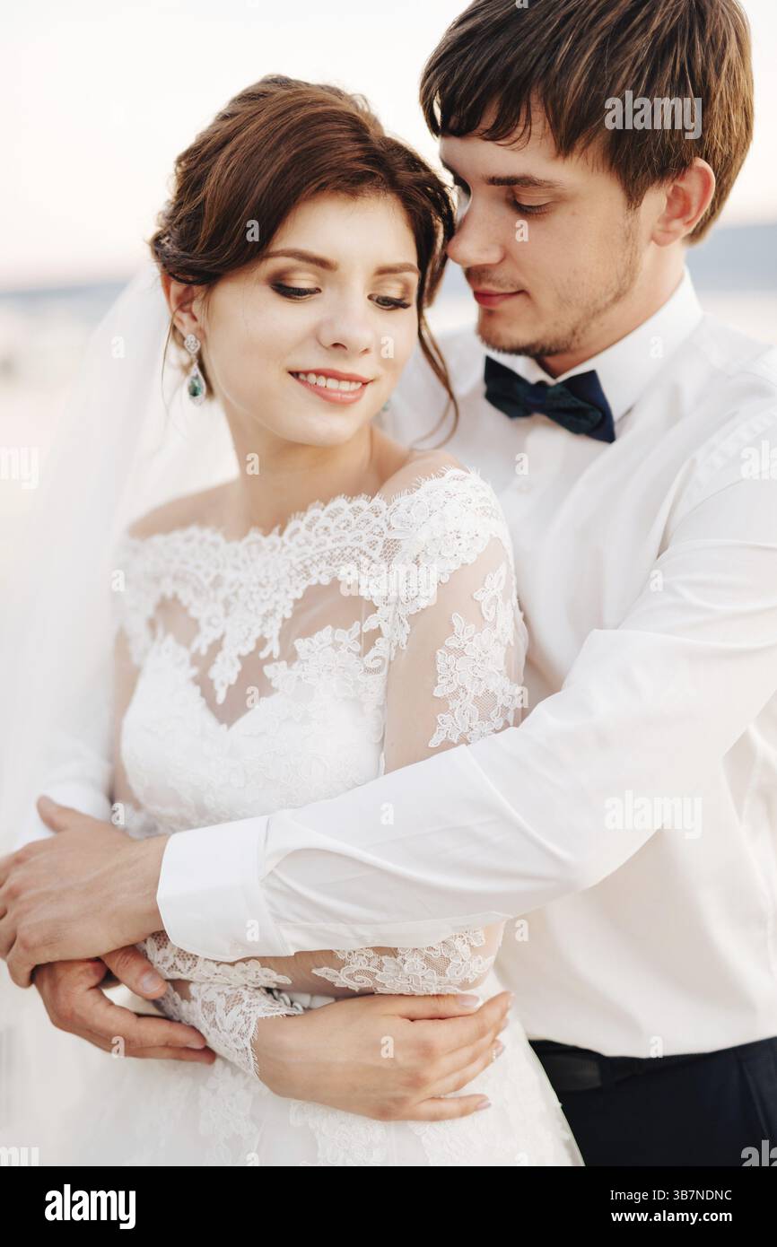 The groom gently hugs the bride from behind Stock Photo - Alamy