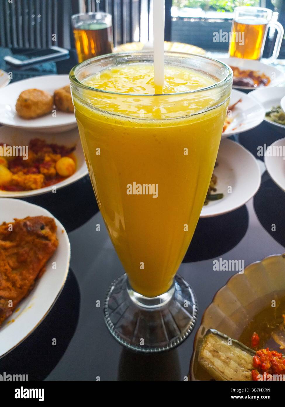 Mango Juice with Indonesian Nasi Padang dishes on a restaurant table ...