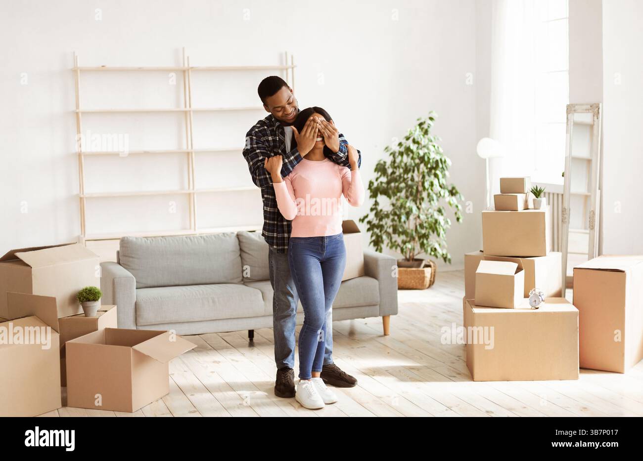 Moving day concept. Millennial black man closing his girlfriend's eyes ...