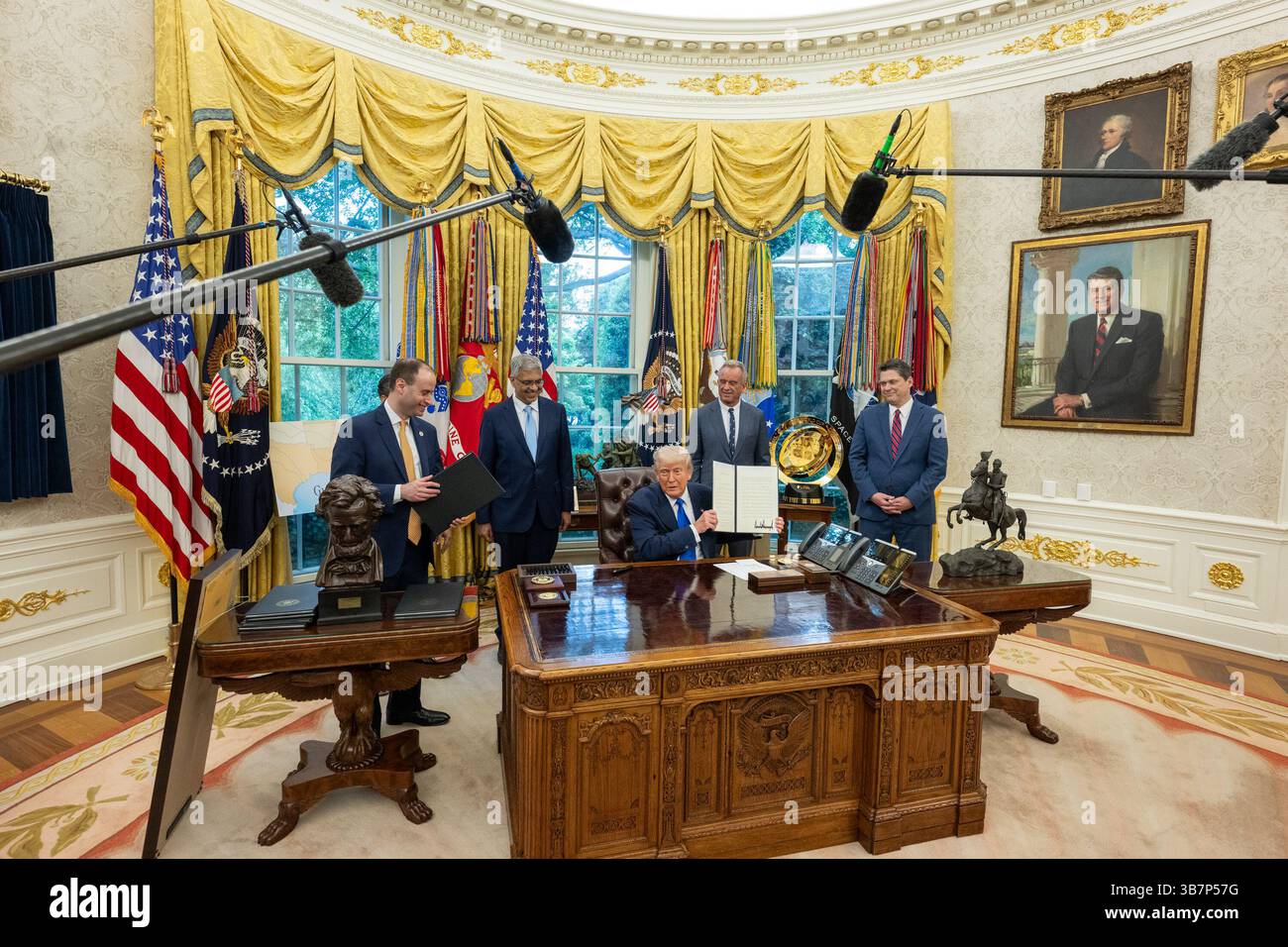President Donald Trump signs executive orders flanked by Secretary of ...