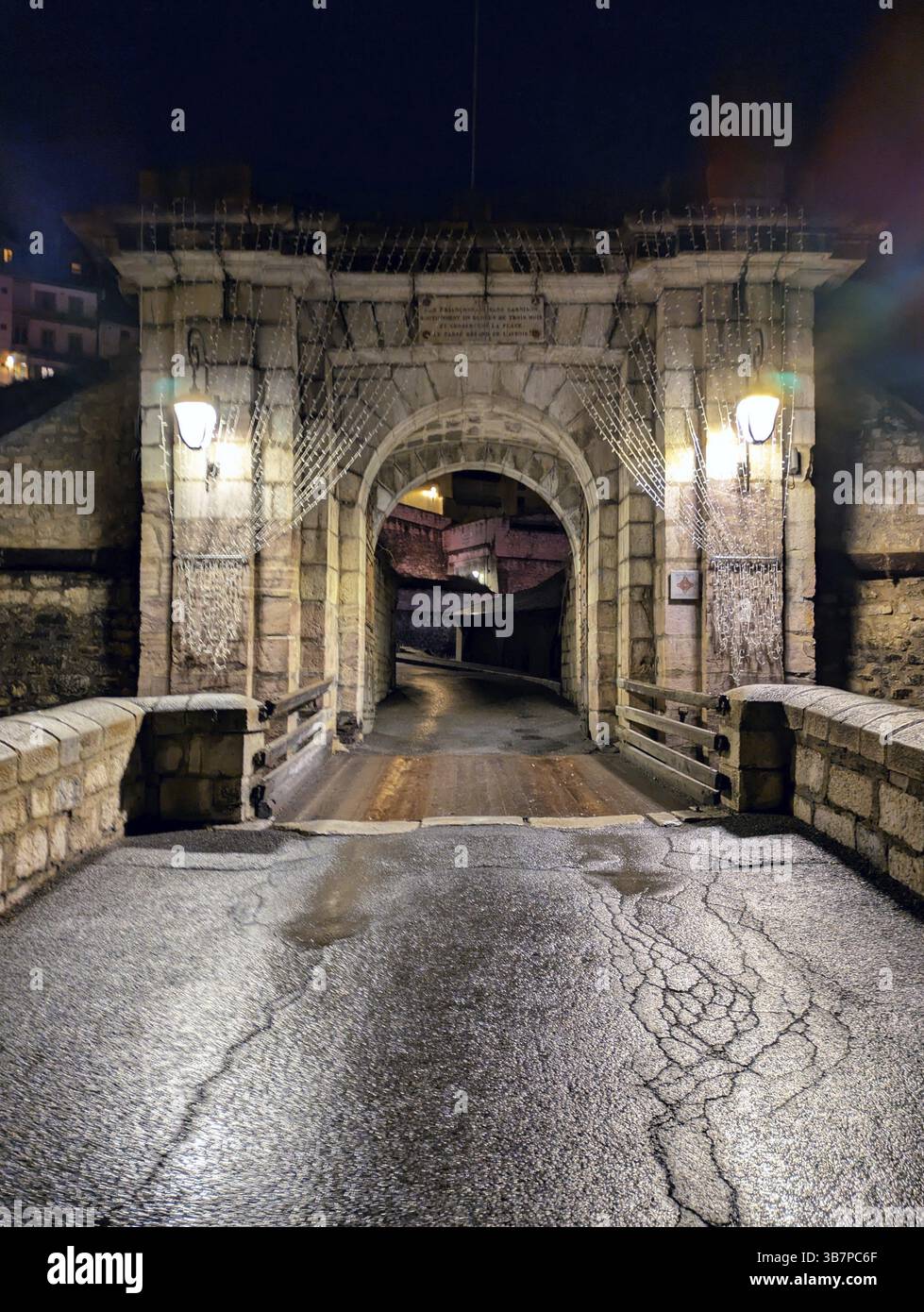 Illuminated historical archway and bridge at night, emphasizing a moody ...