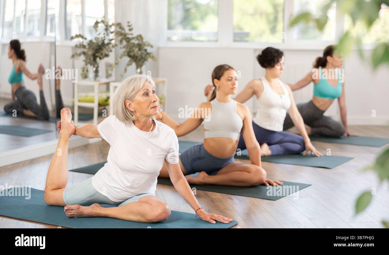 Group of women practicing yoga, working out doing version of Eka Pada ...
