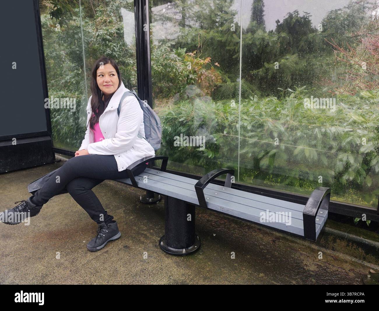 Single 40-year-old Latina woman sitting alone at a bus stop with empty ...