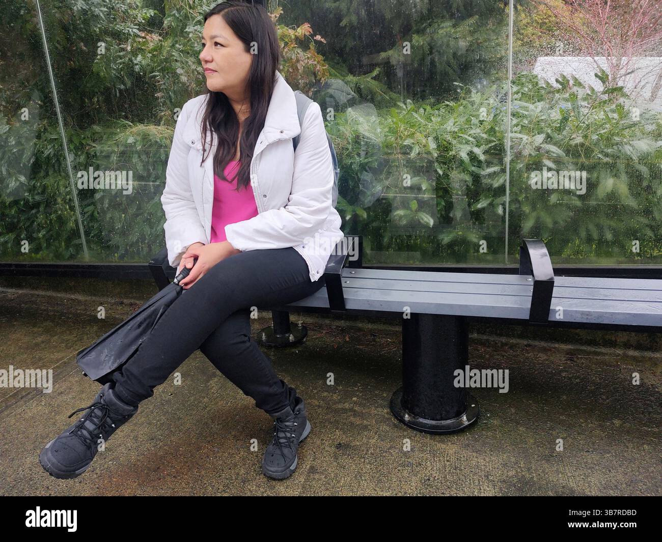 Single 40-year-old Latina woman sitting alone at a bus stop with empty ...
