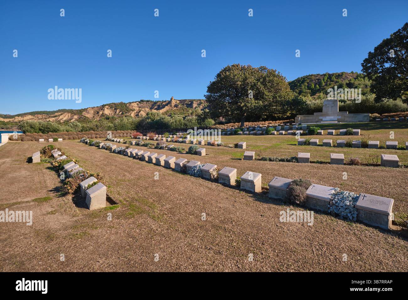 A view of small graves and the main memorial, with cross. At the ...