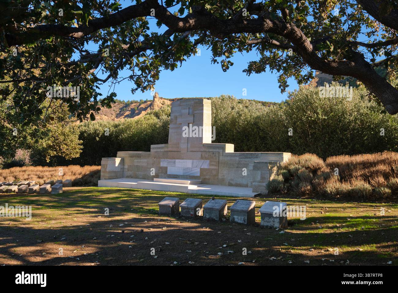 A view of small graves and the main memorial, with cross. At the ...