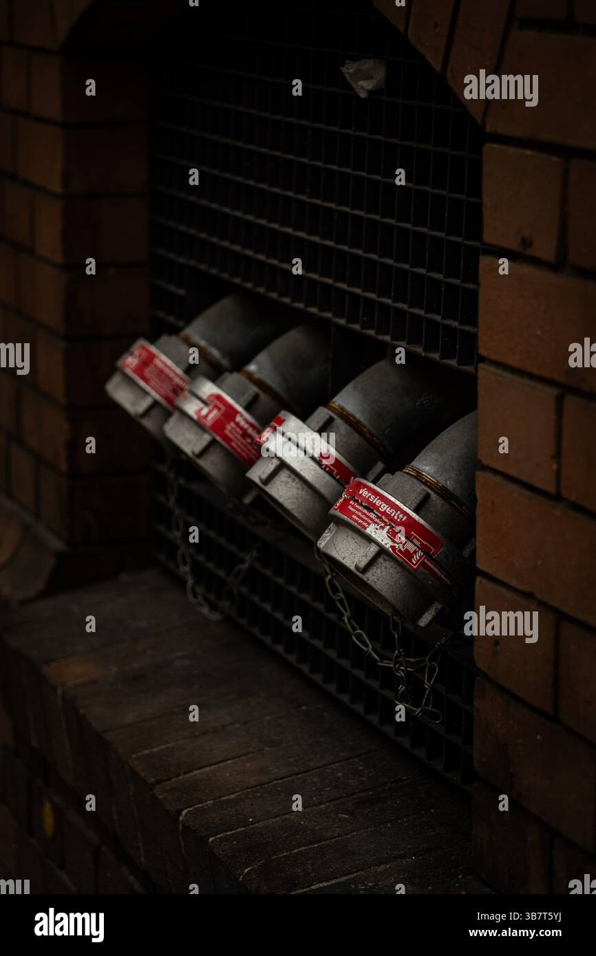 A close-up of sealed metal pipe outlets installed in a brick wall ...