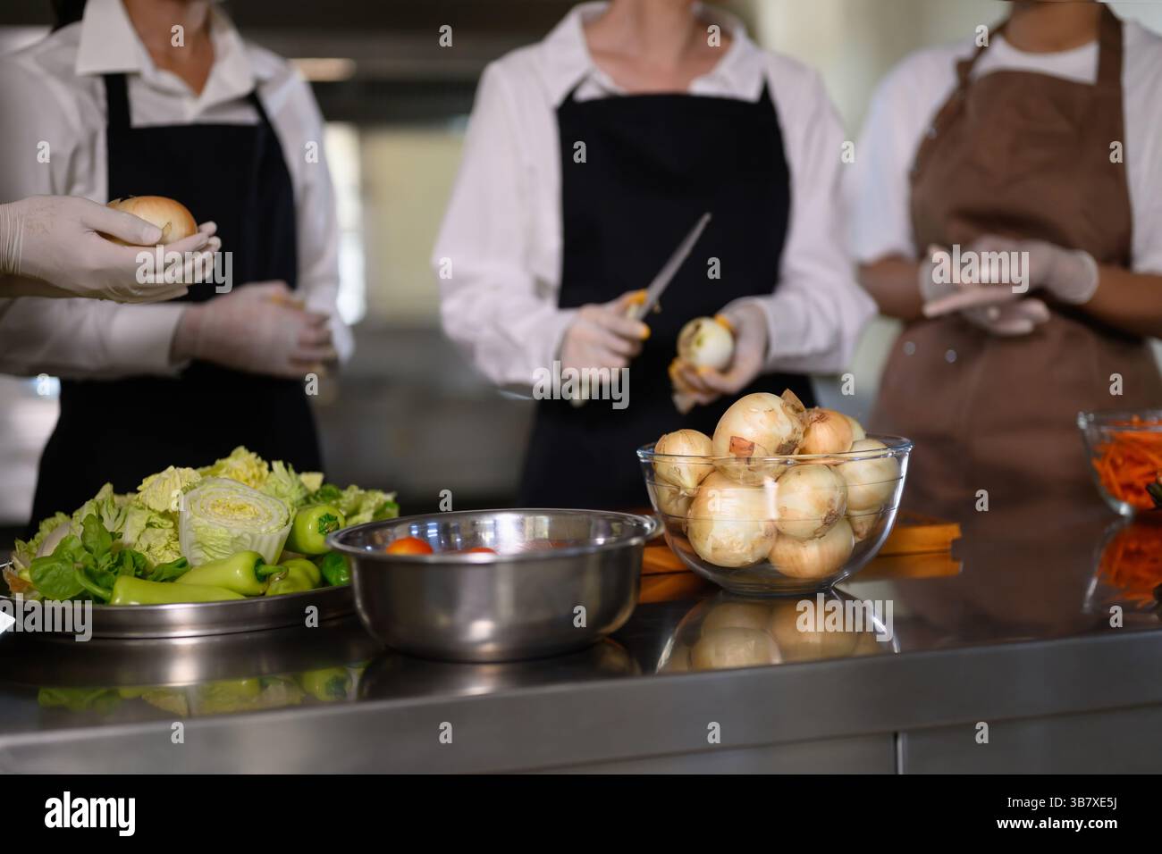 Group of cooking school students preparing fresh vegetables during a ...