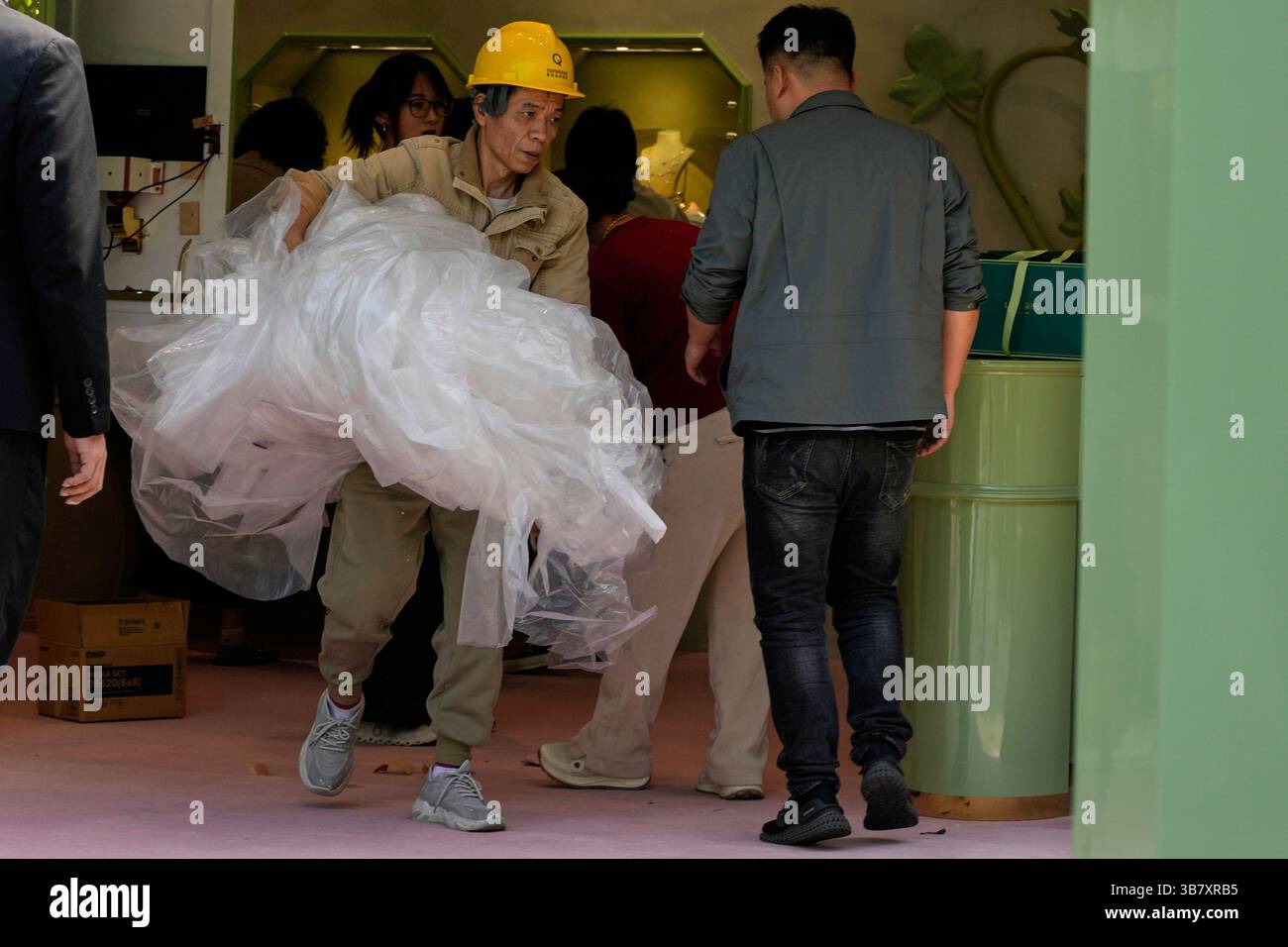 A worker removes plastic sheets after setting up a booth at a mall in ...