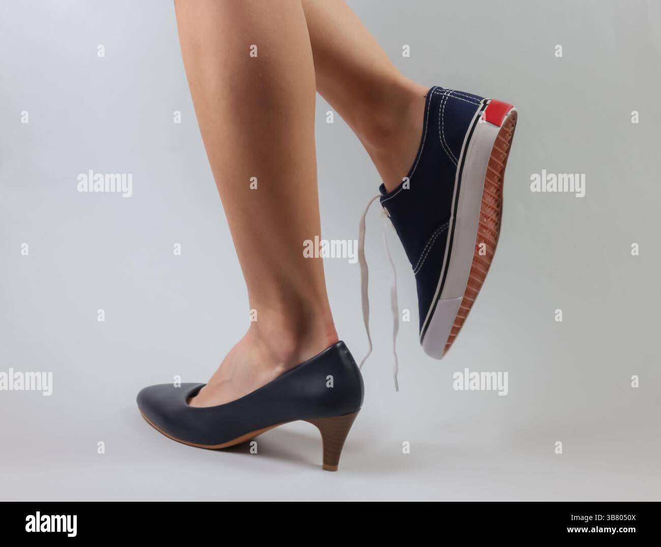 Slim woman's legs in two different shoes with heels and sneakers on ...