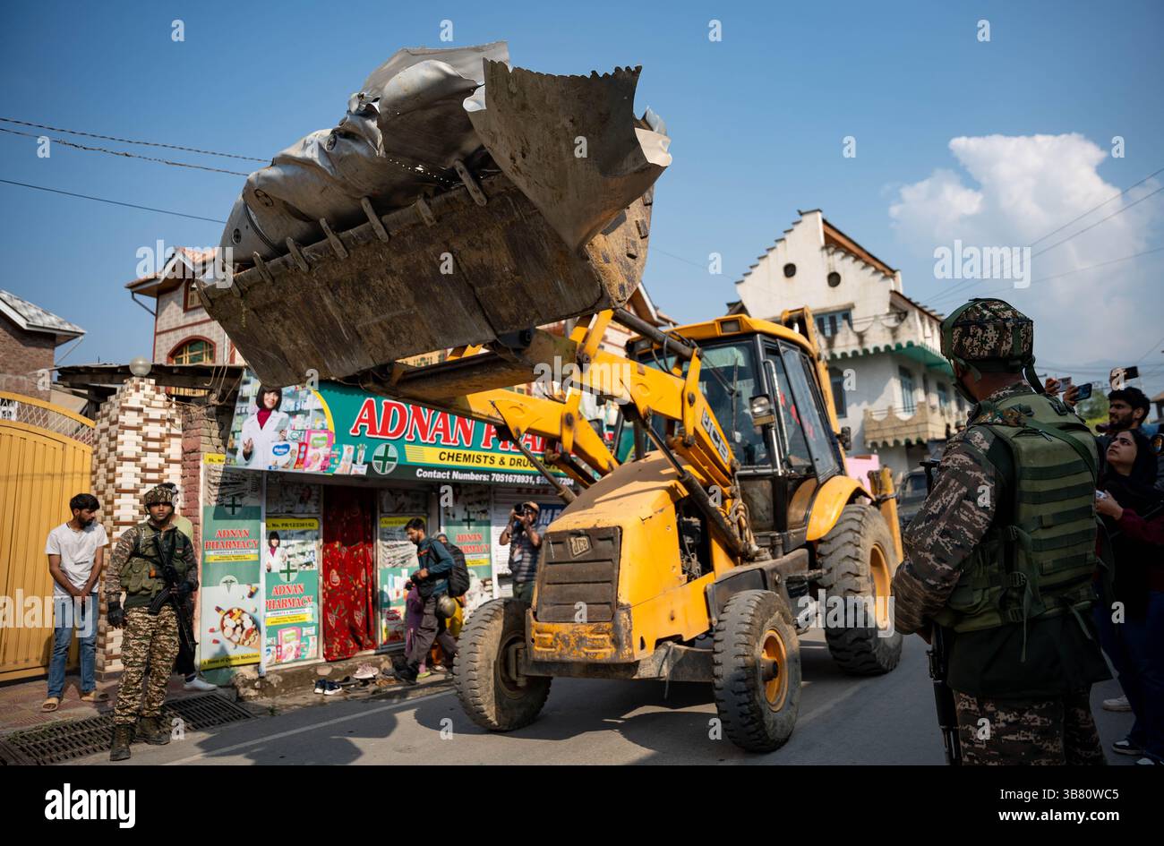 Wreckage is being carried by a bulldozer near the site where the ...