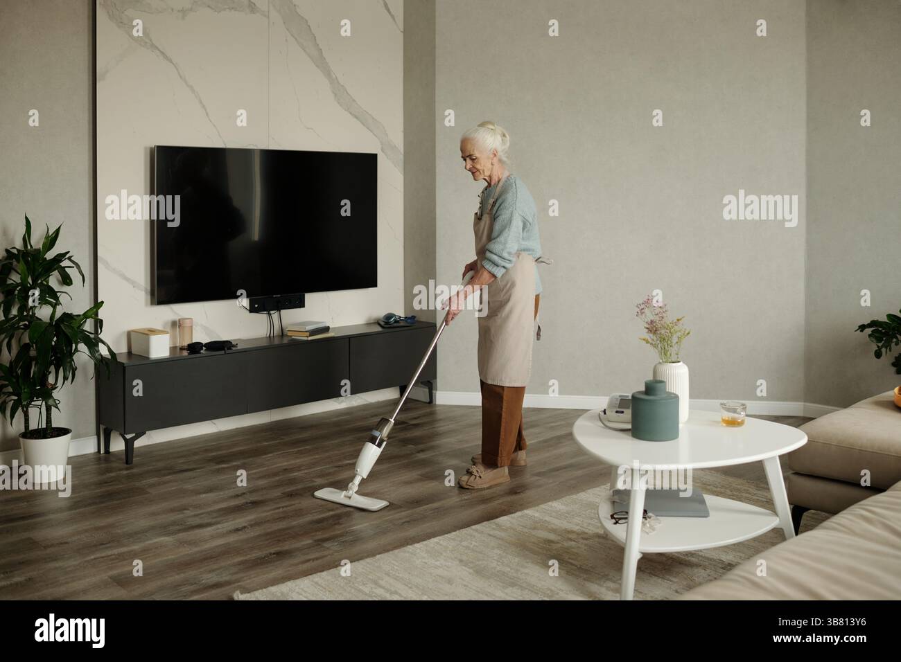 Elderly Woman Cleaning Living Room With Vacuum Cleaner Stock Photo - Alamy