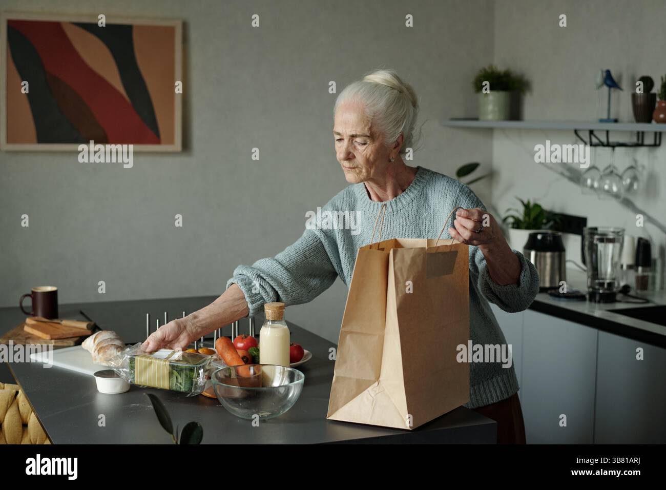 Senior Woman Packing Groceries in Kitchen Setting Stock Photo - Alamy