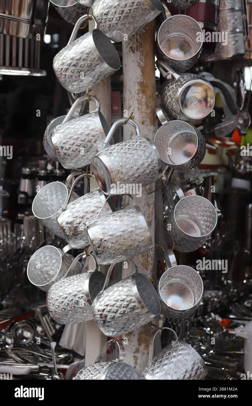 Displayed in a close-up shot, numerous shiny silver mugs feature ...