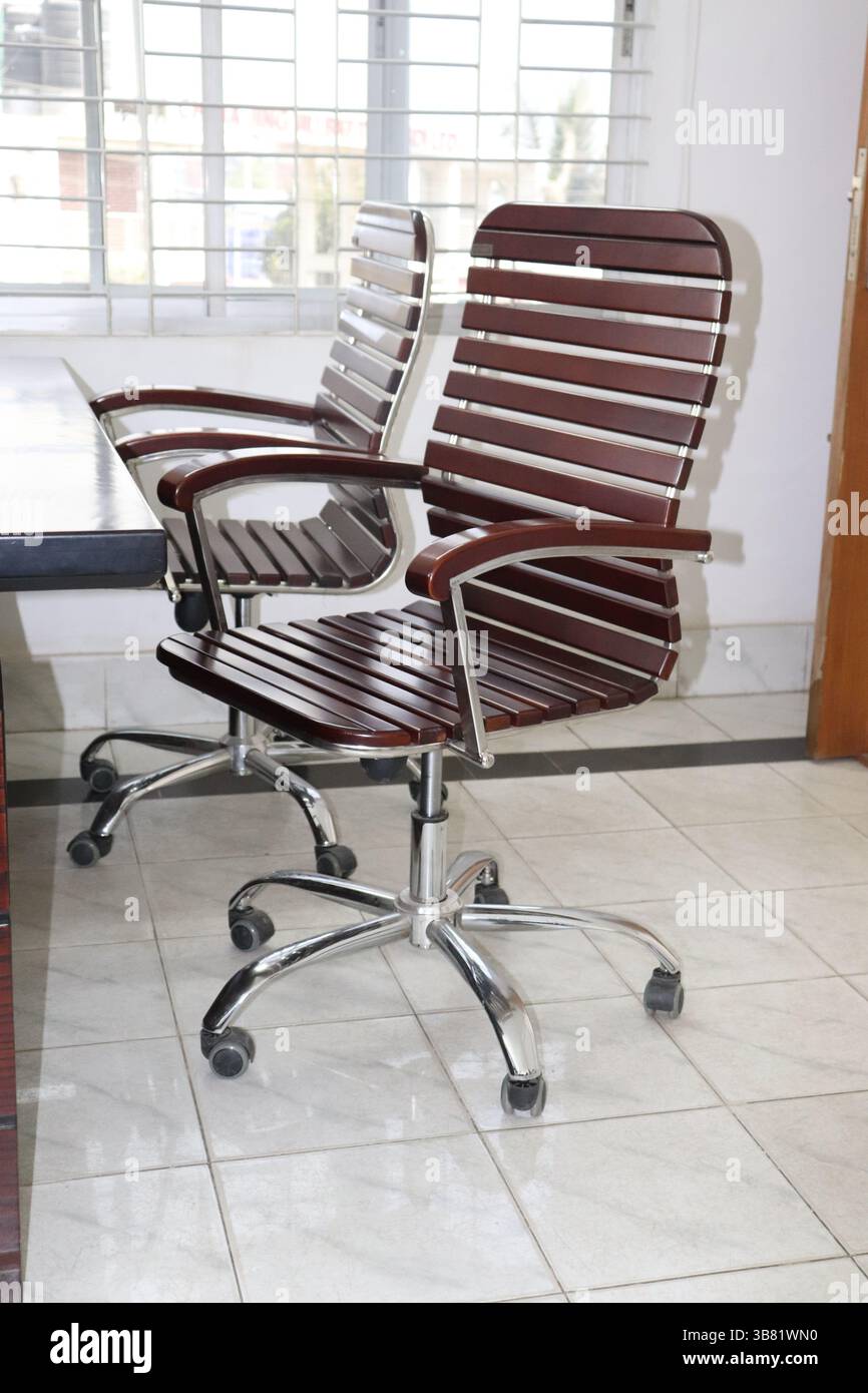 The scene captures two wooden office chairs, each featuring horizontal ...