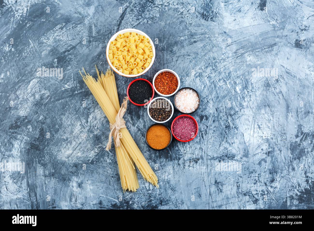 top view ditalini pasta in bowl with spaghetti, spices on grey plaster ...