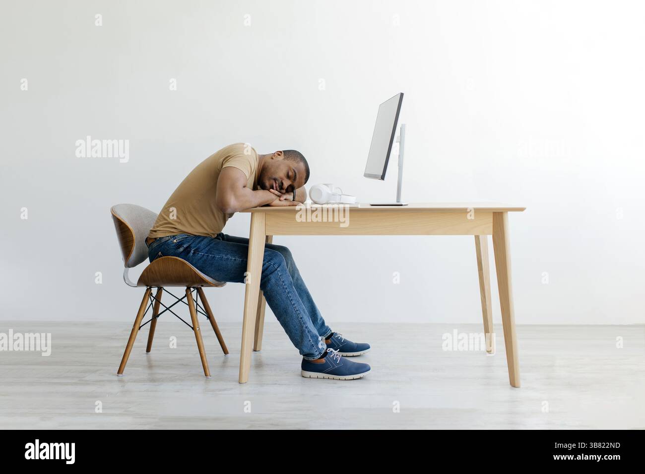 Tired African American man resting his head on desk next to computer ...