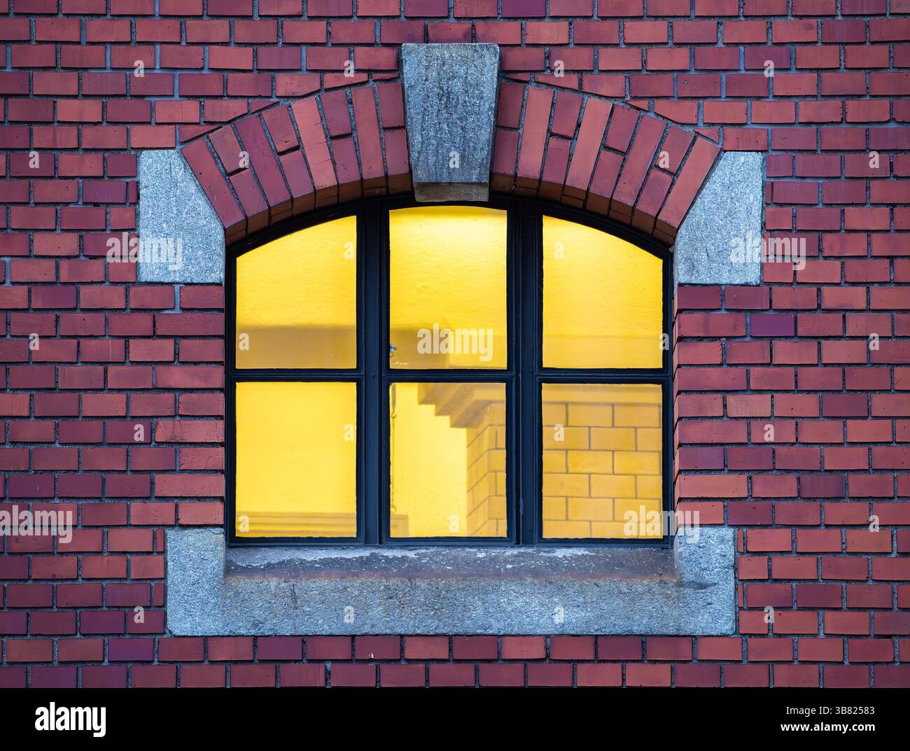 A close-up view of a brick wall featuring an arched window. The window ...