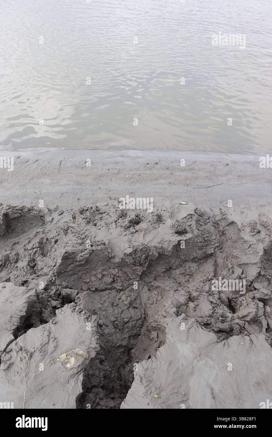 An overhead shot depicts murky water touching the eroded grey soil ...