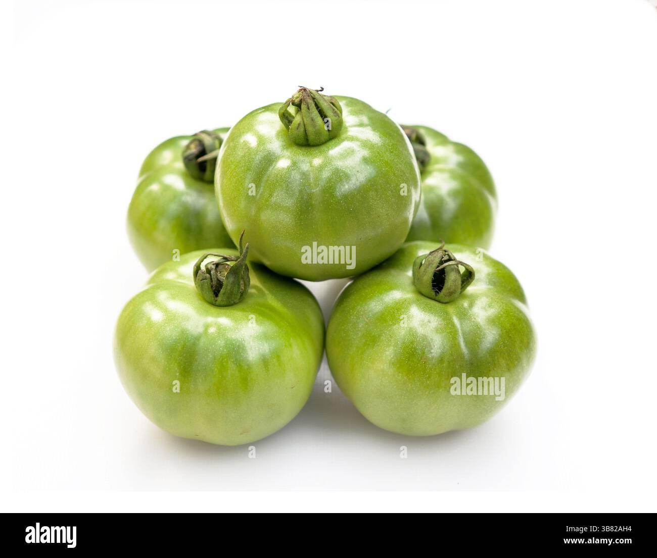 Close up of five unripe green tomatoes that are stacked to form a ...
