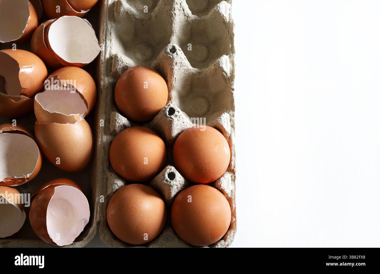 Broken eggshells and whole eggs in a cardboard egg container. Directly ...
