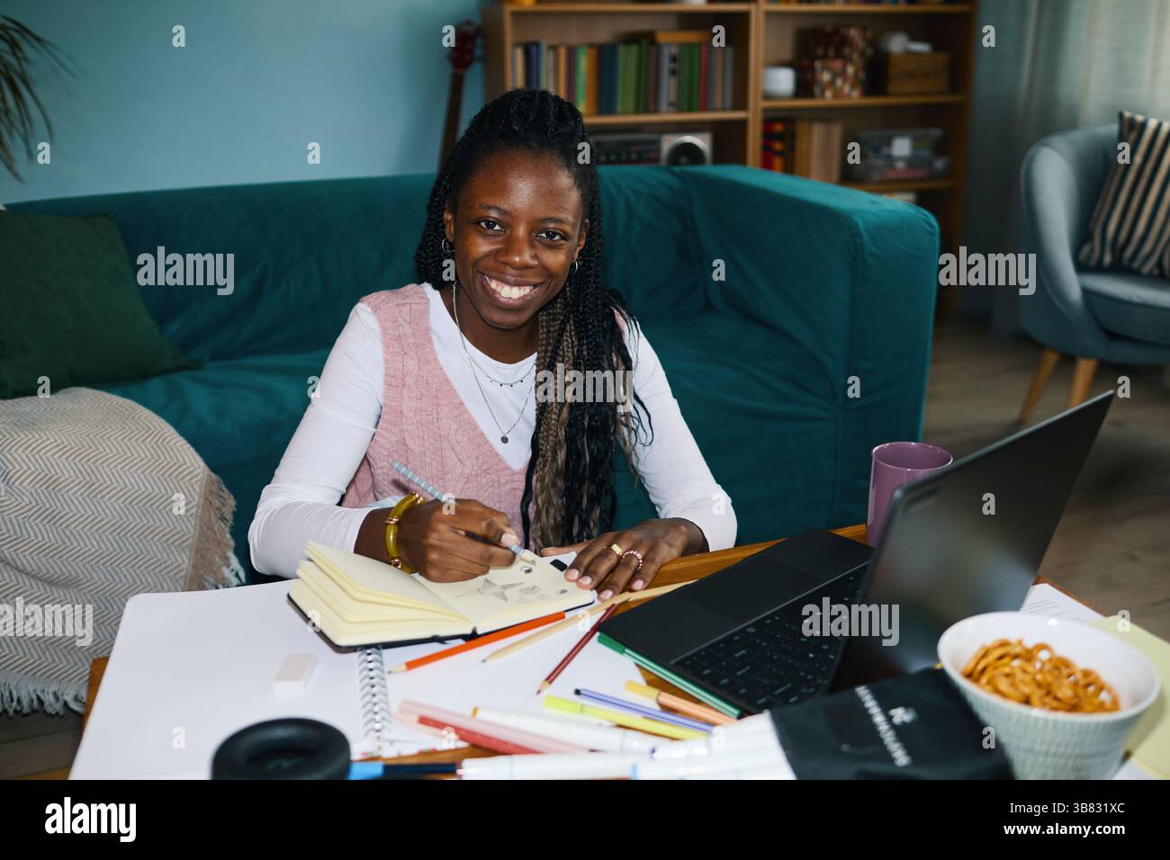 Smiling woman taking notes at desk filled with stationery items and ...