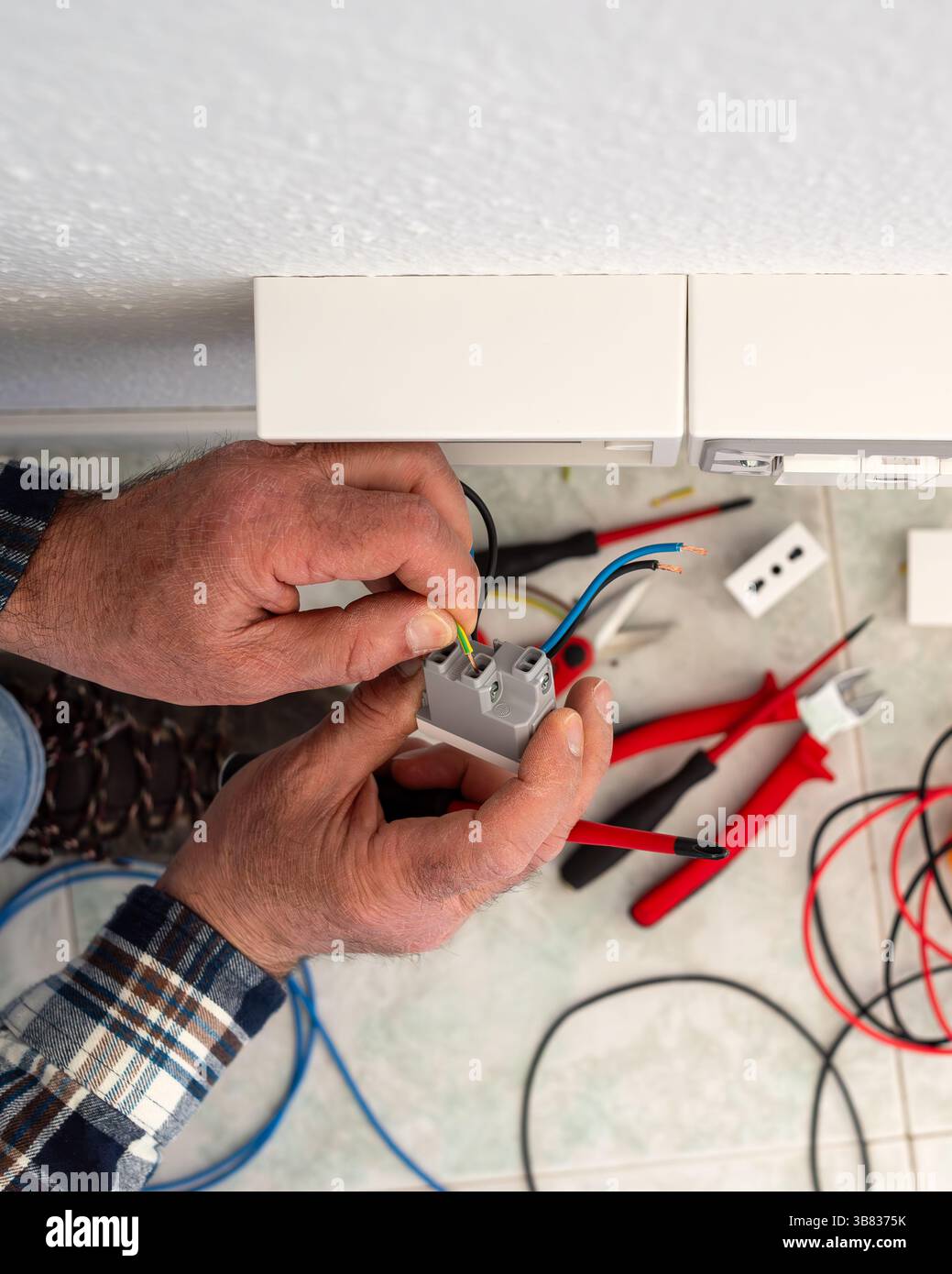 Electrician worker inserts electrical cables into the socket terminals ...