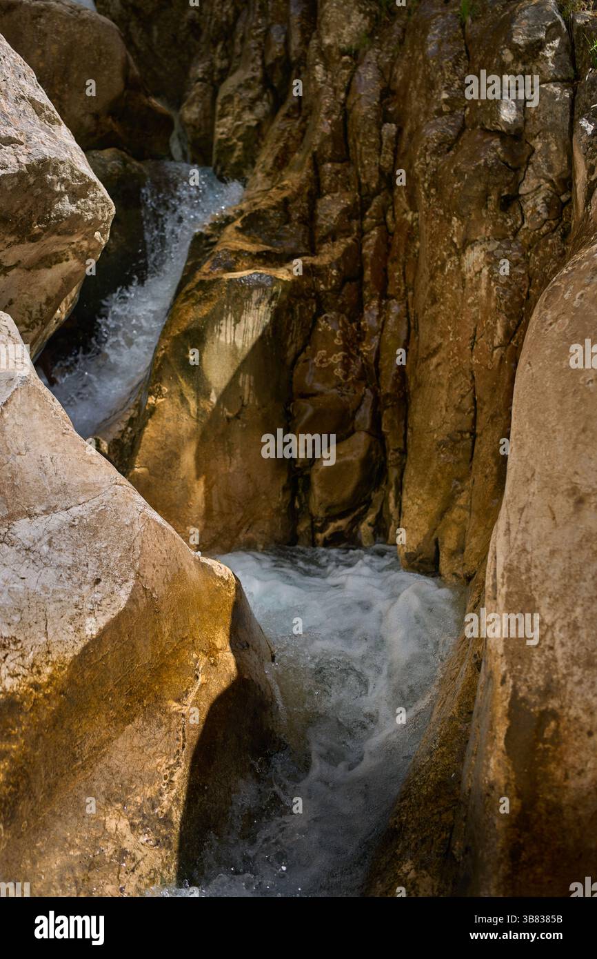 Powerful mountain stream cascading through narrow rocky limestone gorge ...