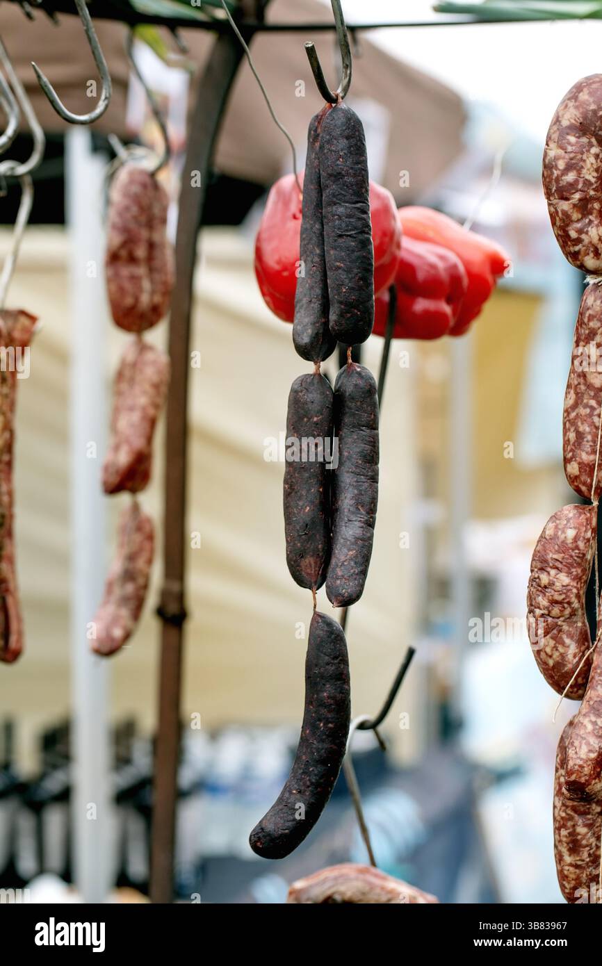 Various traditional sausages and cured meats hanging on hooks. Black ...