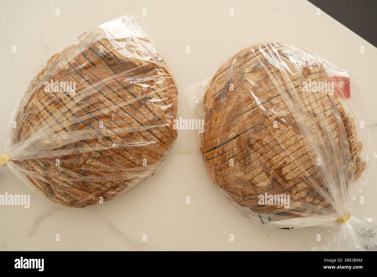 Two loaves of sliced bread neatly wrapped in clear plastic packaging ...