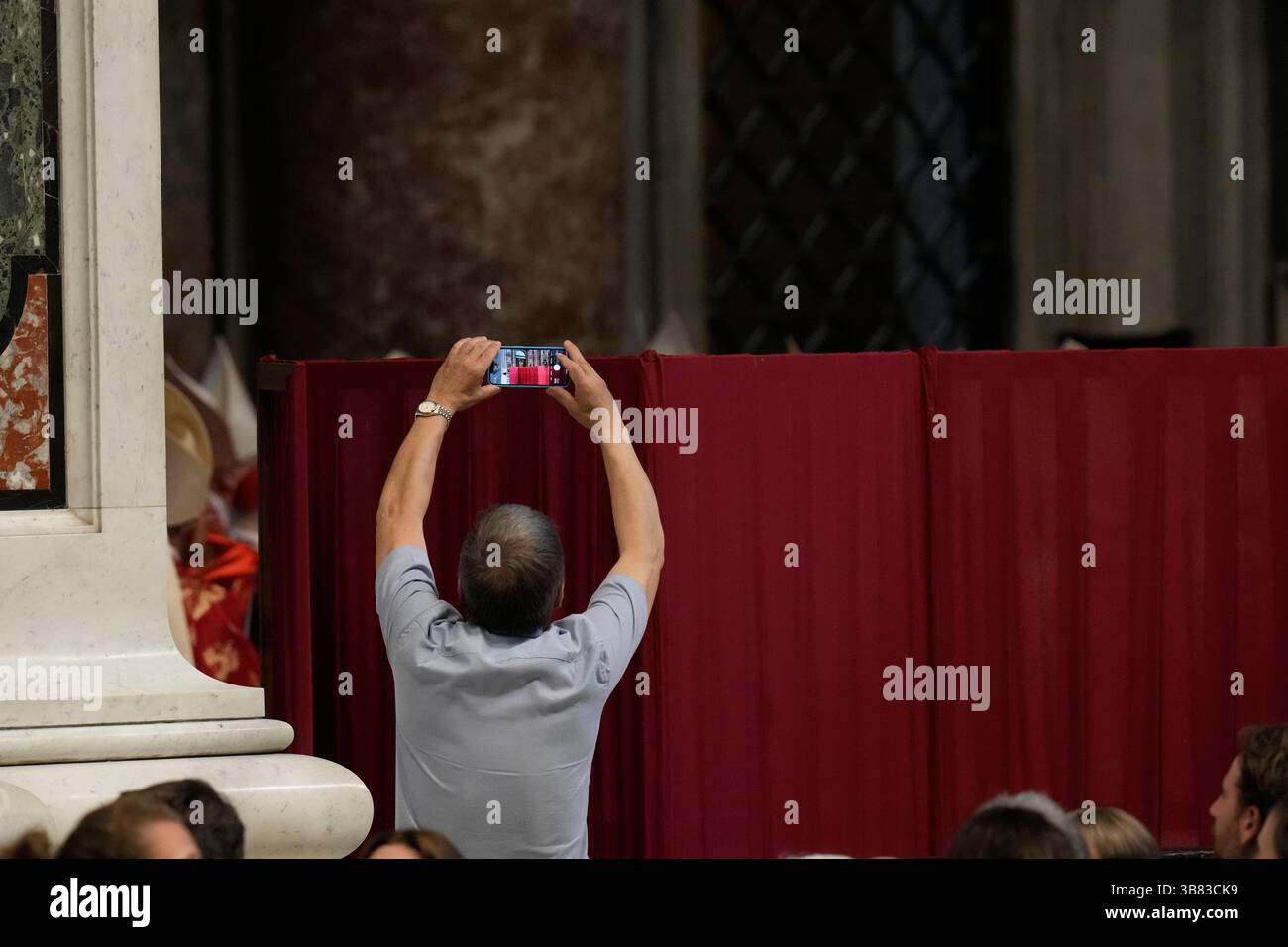 A faithful tries to capture images of cardinals behind a screen during ...