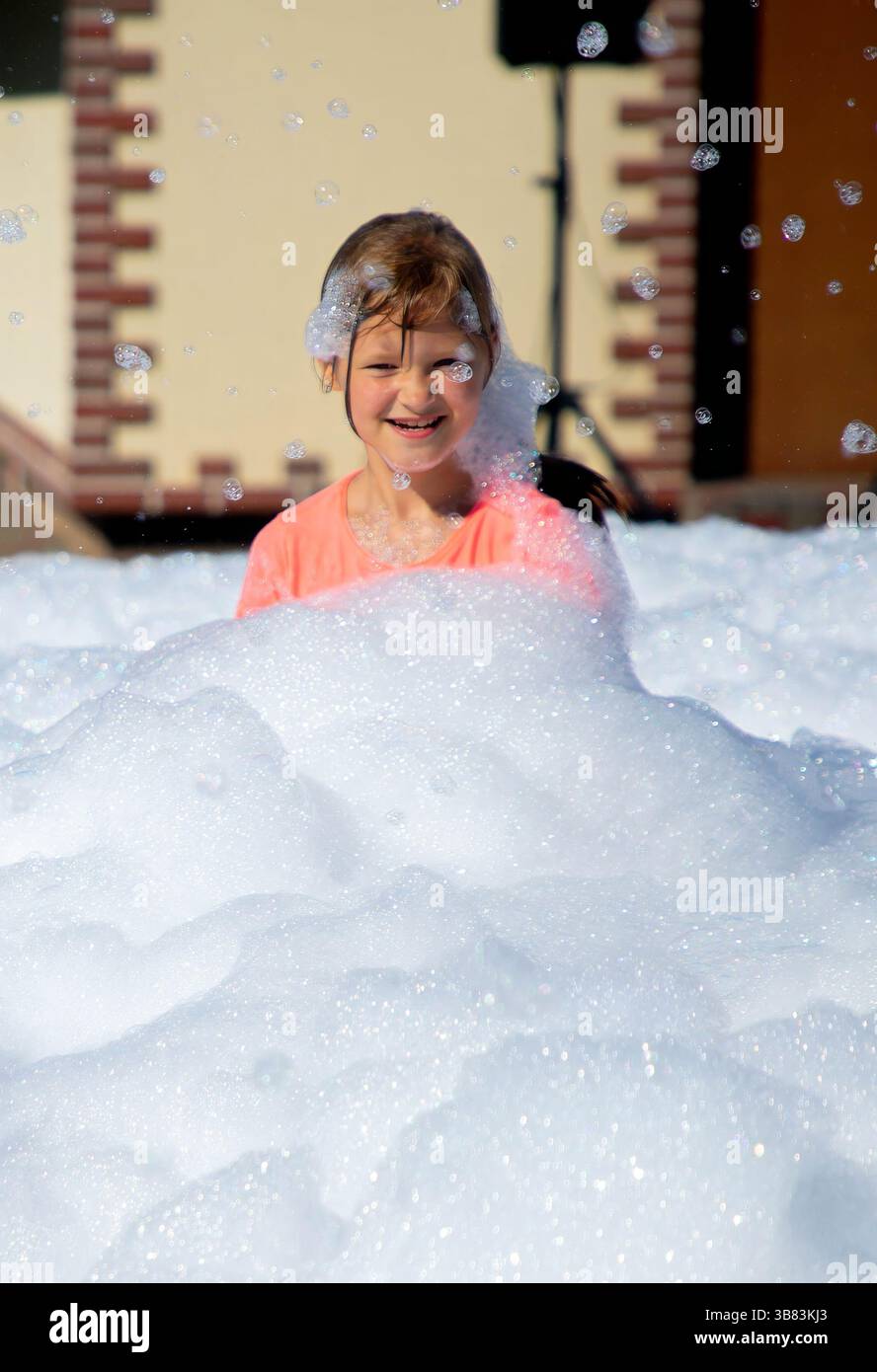 Female child playing in outdoor foam party smiling Stock Photo - Alamy