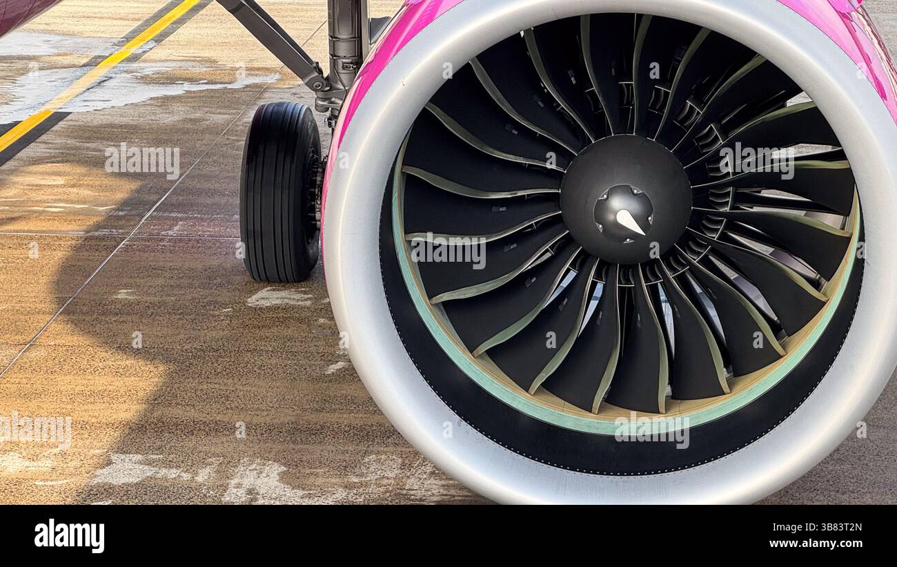 Close-up view of a large modern jet engine with distinctive pink and ...