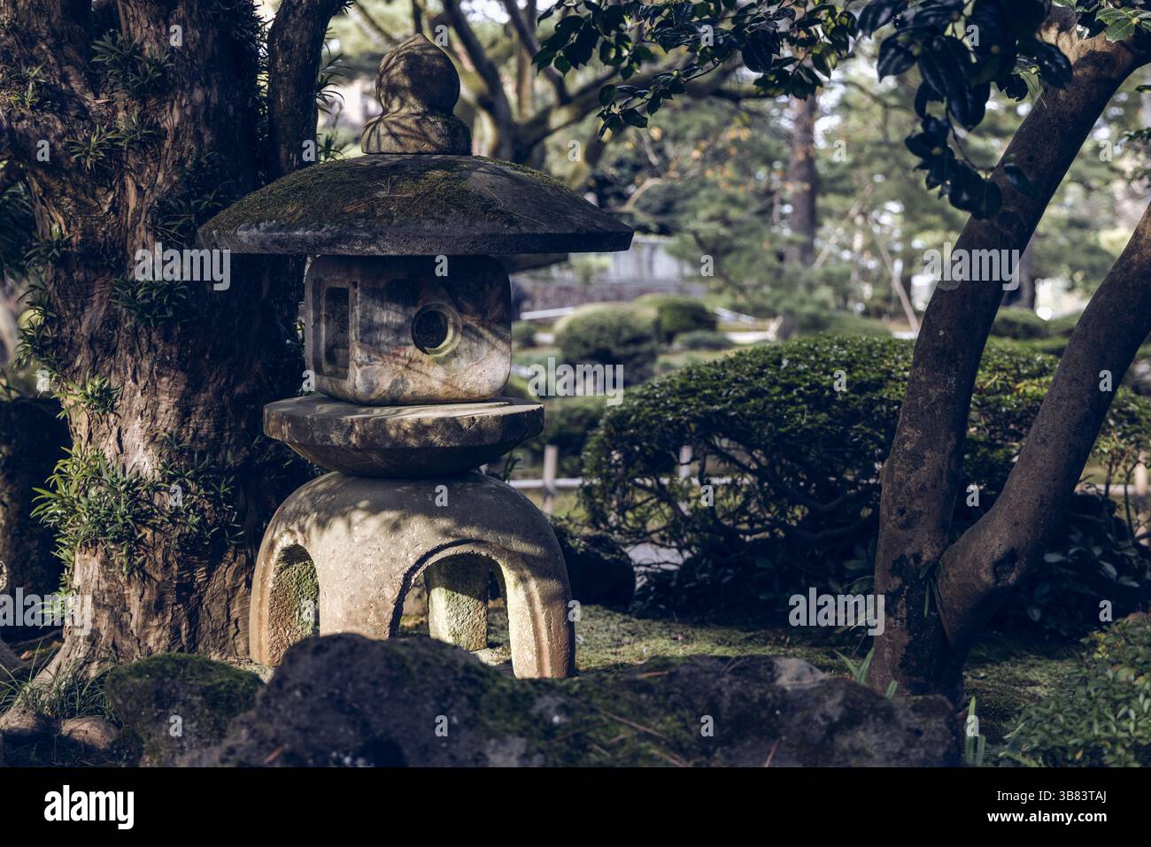 Stone lantern in a Japanese garden setting with aged textures and soft ...