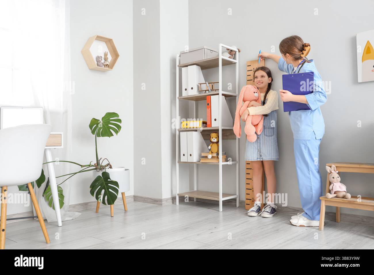 Female pediatrician measuring height of cute girl near stadiometer in ...