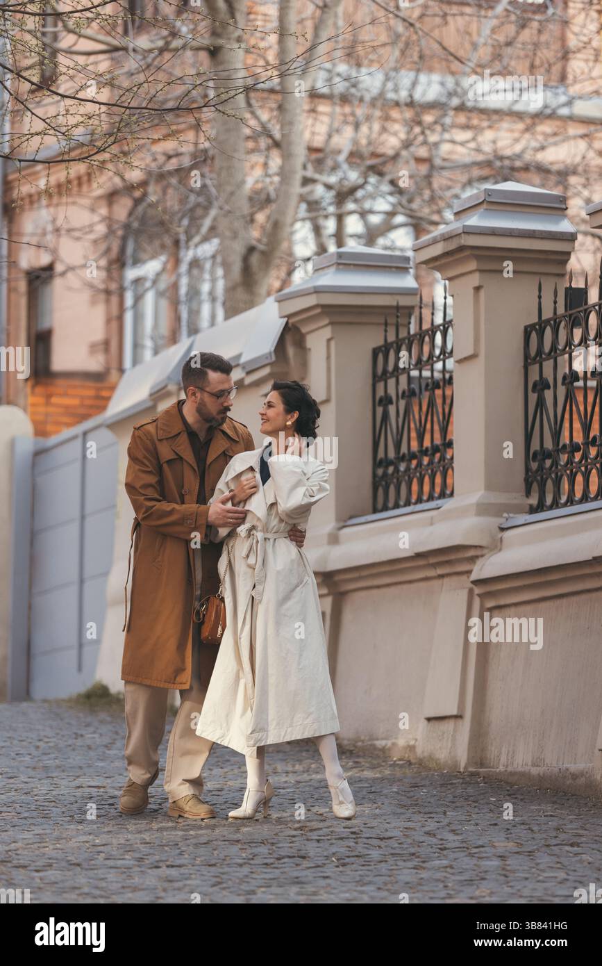 Man and woman in vintage-style clothes walk side by side on cobblestone ...