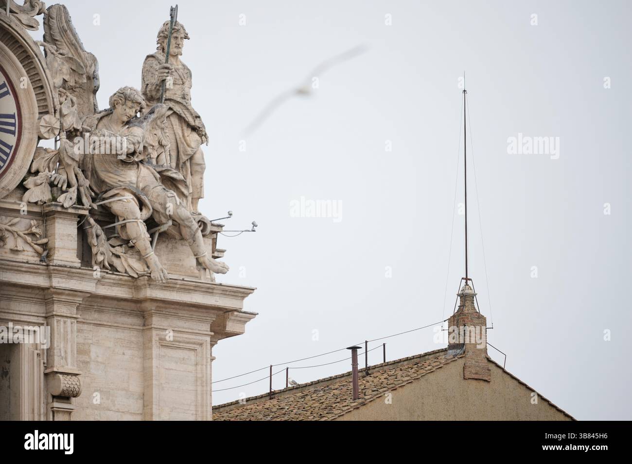A seagull flies past as another sits on the roof by the chimney of the ...