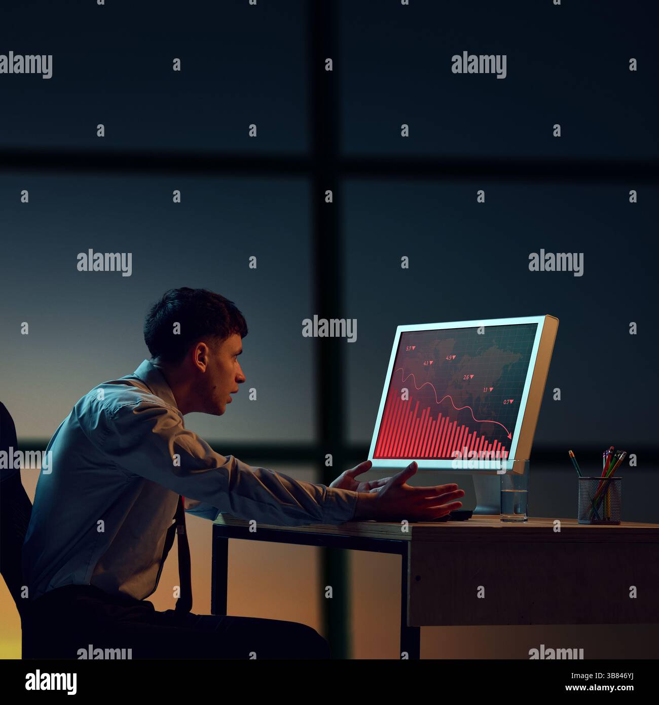 Frustrated businessman in office at night gestures angrily at computer ...