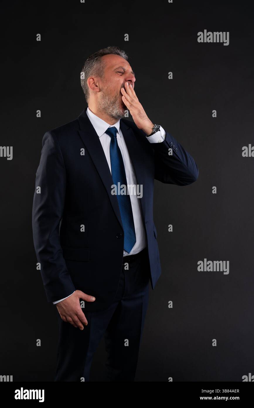 Full body portrait of a tired businessman in suit and tie, yawning and ...