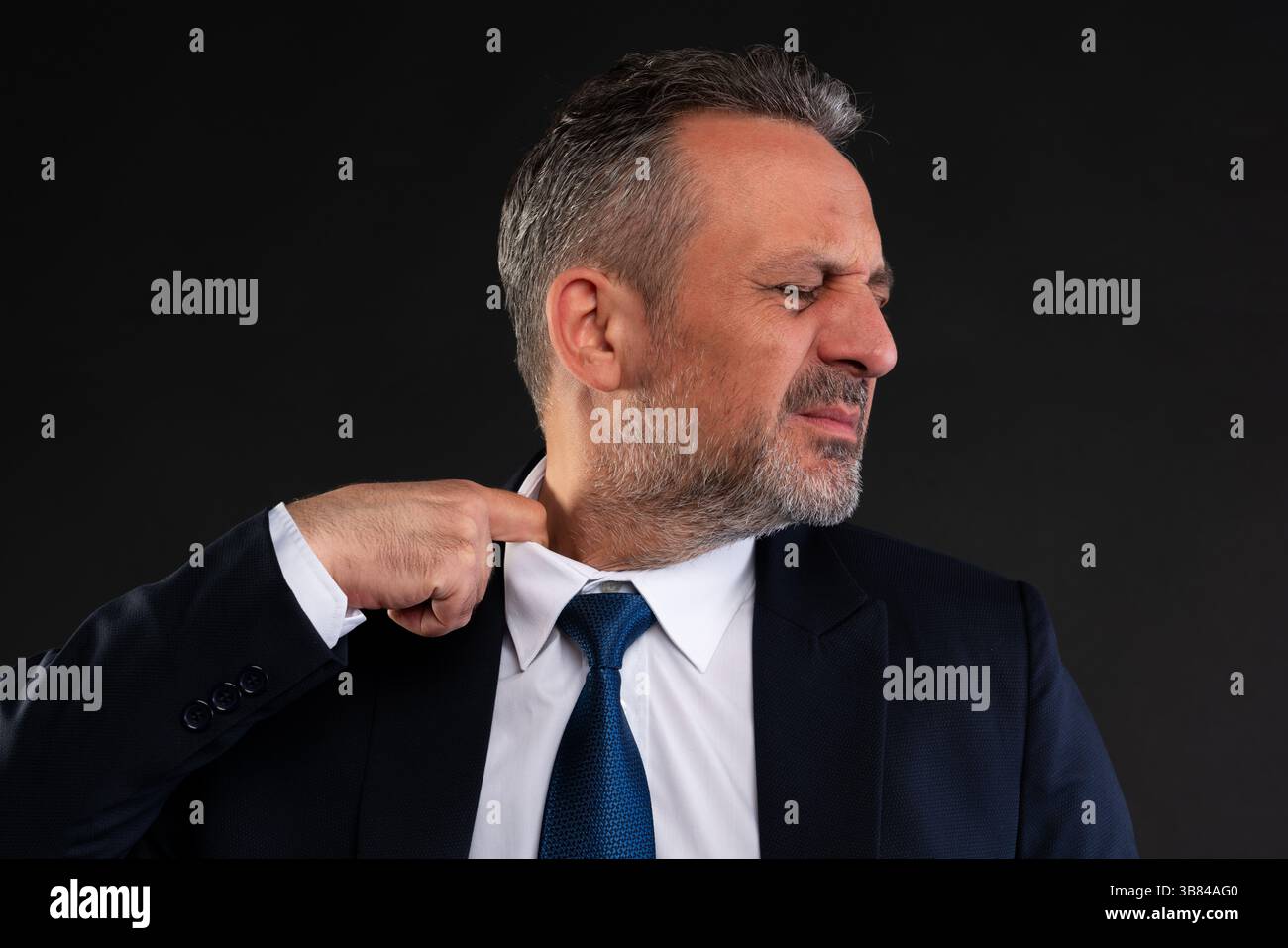 Middle-aged businessman in suit pulling his shirt collar with ...