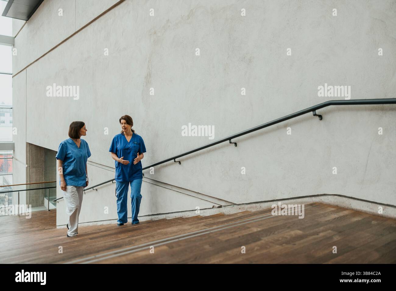 Full length of female doctors wearing medical scrub moving up on stairs ...