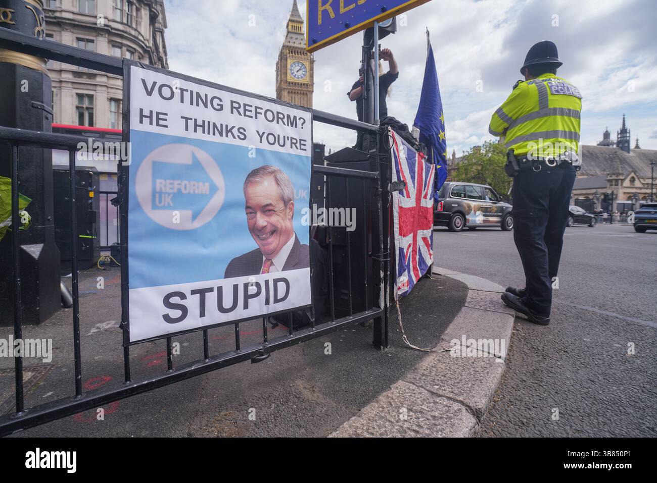 London UK 7 May 2025. A policeman stands next to a picture of Reform UK ...