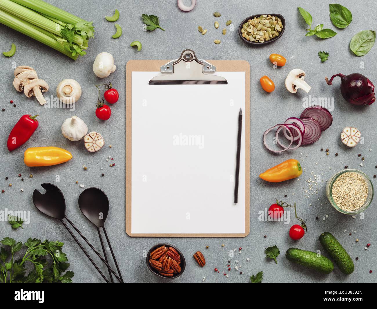 Food ingredients, salad serving utensils and clipboard with white paper ...